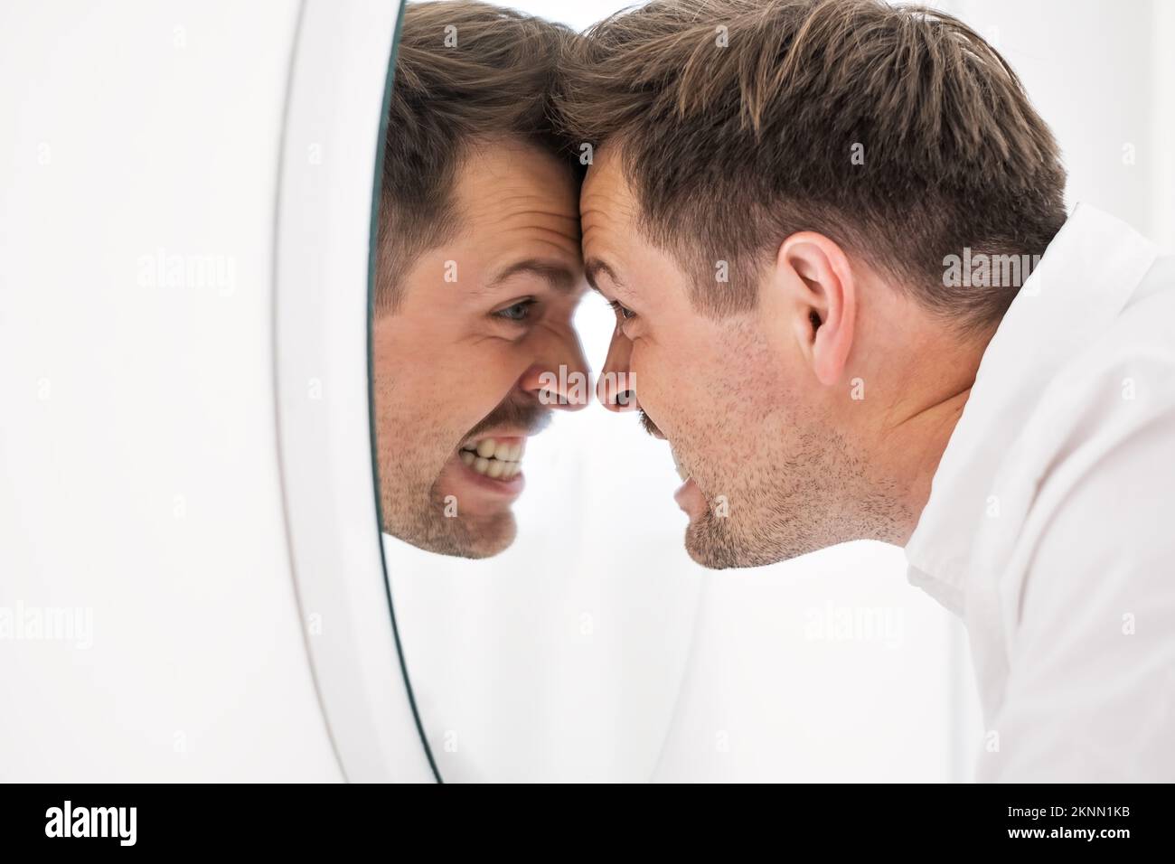 Caucasian man being angry on himself screaming on his reflection on the ...