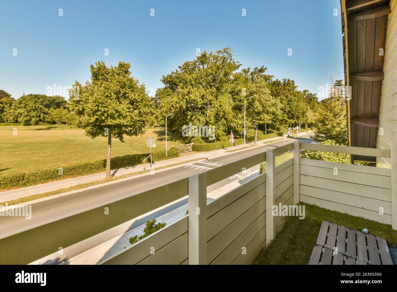 Panorama view of meadow with an empty sidewalk street with cars, trees ...