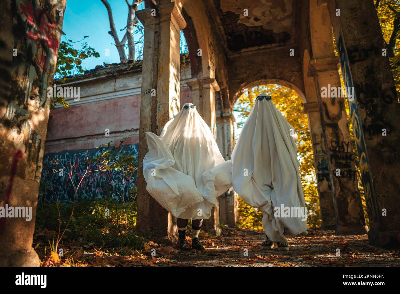 A funny image of two jumping people in ghost costumes and sunglasses in ...