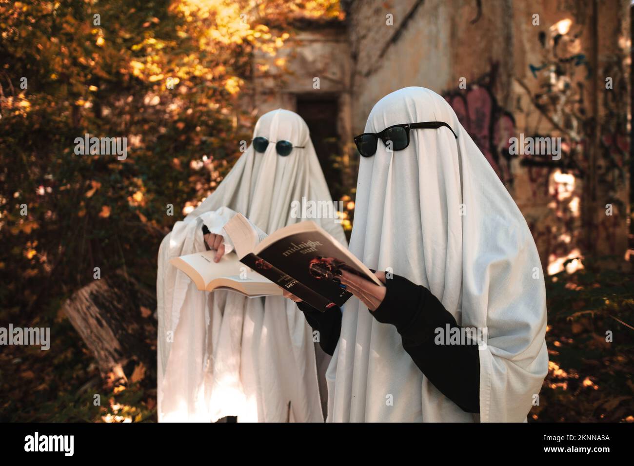 A funny image of two people in ghost costumes and sunglasses are ...