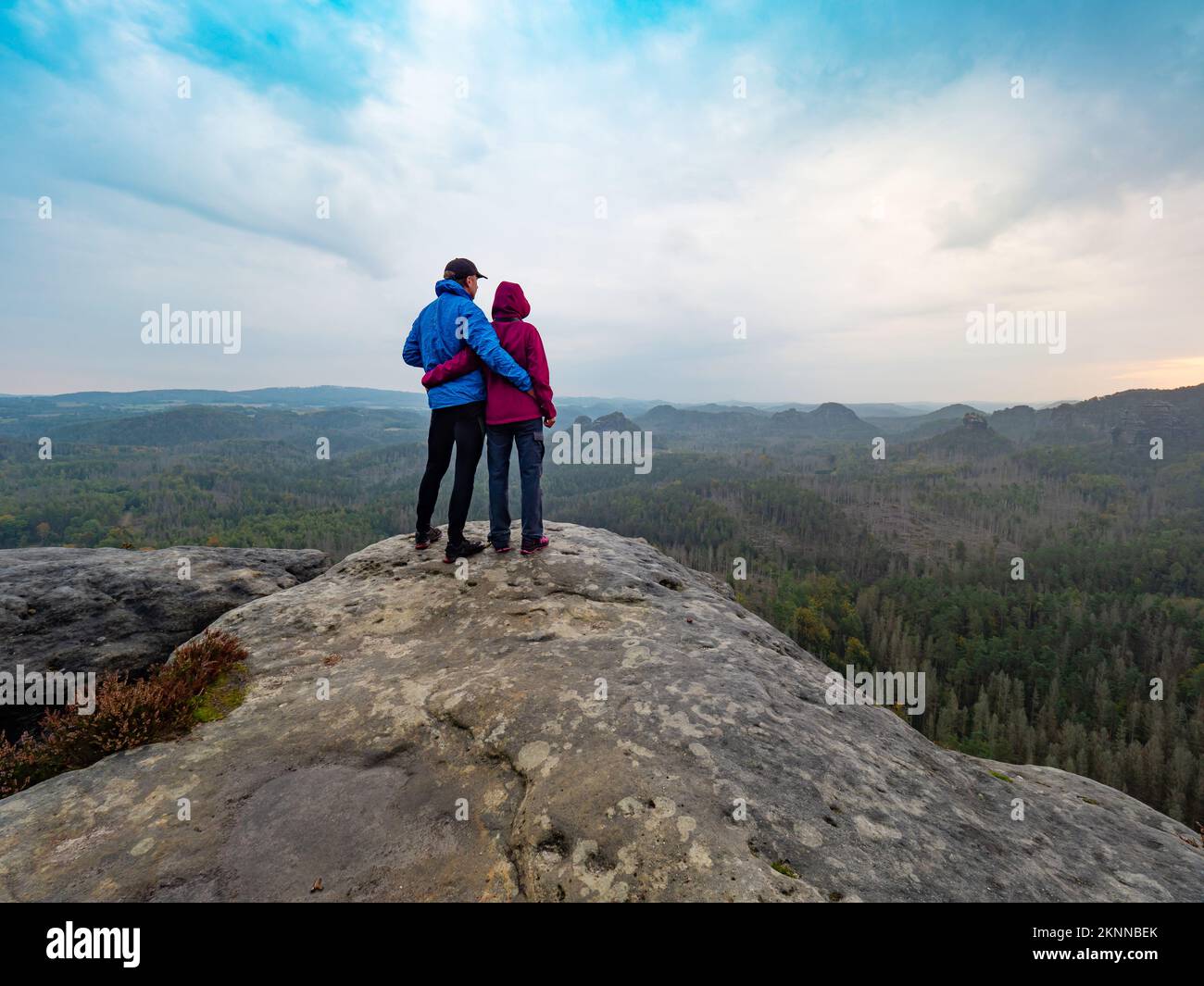 Hikers couple on the mountain edge looking over valley. Woman and man ...