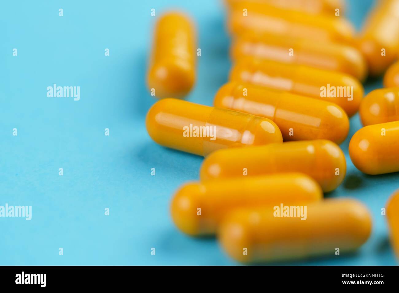 Turmeric herb yellow medicative capsules with curcumin powder on a blue ...