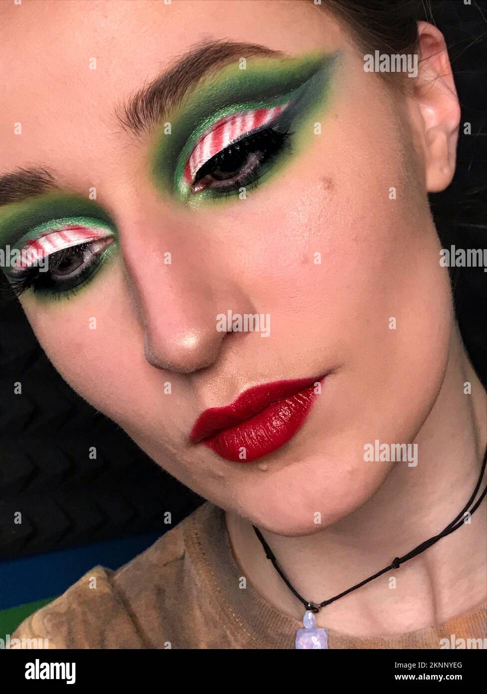 Vertical close-up of a lovely woman wearing Christmas candy cane eye ...
