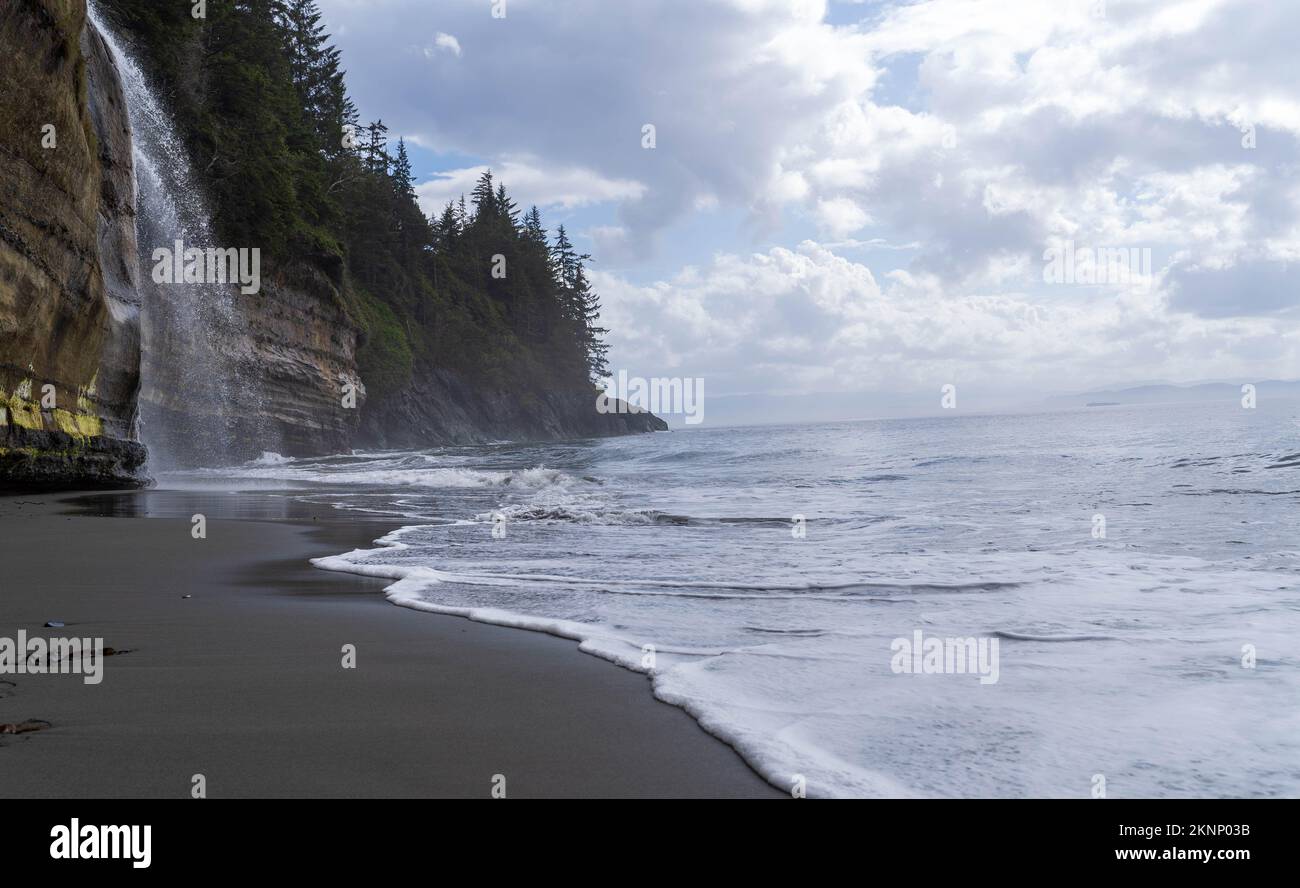 A scenic view of a waterfall falling to the sea from a coastal cliff ...