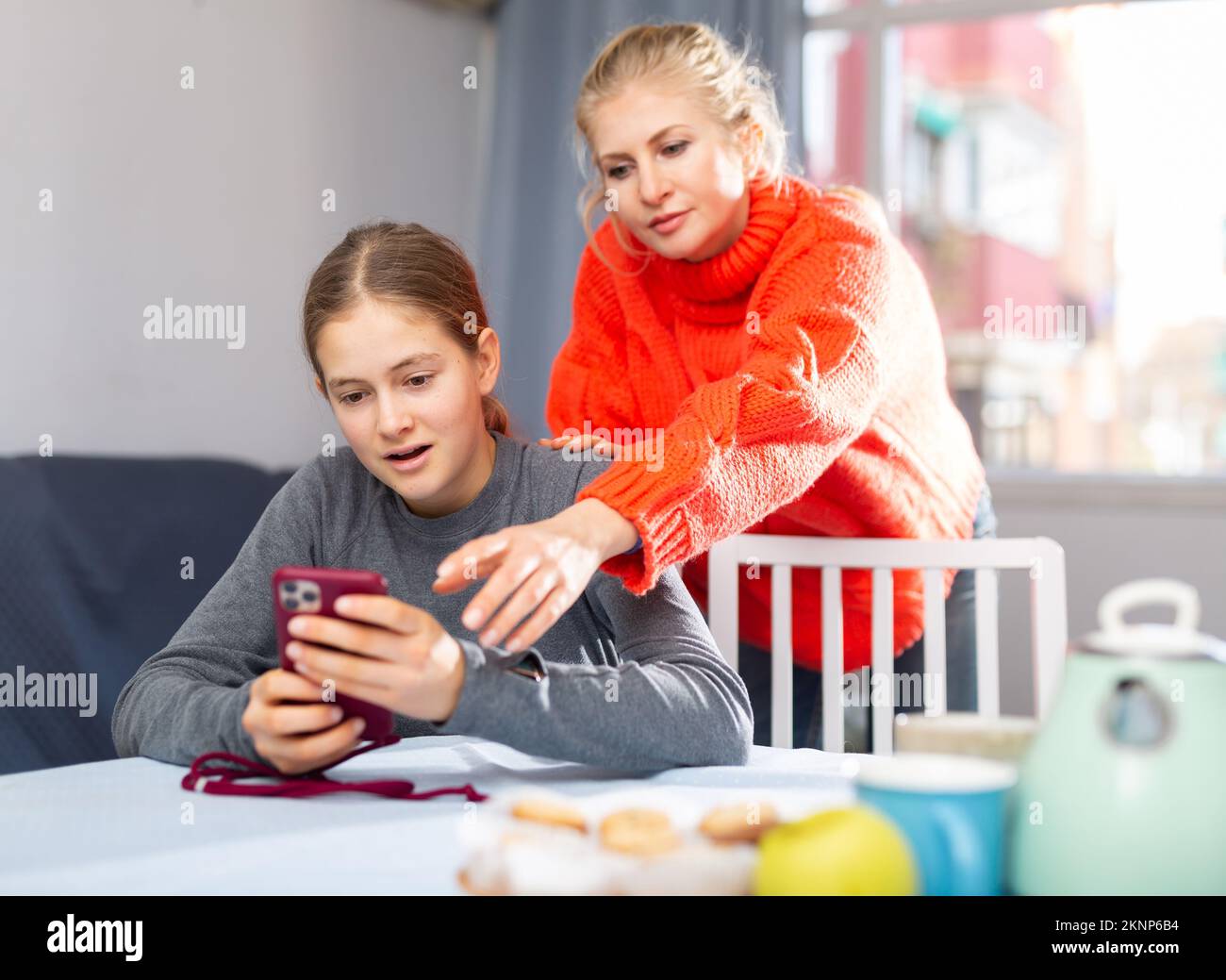Girl sitting with phone, ignoring mother Stock Photo - Alamy