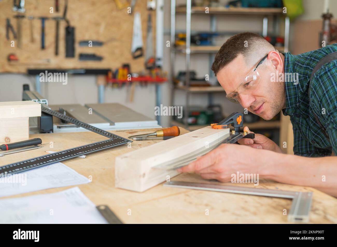 Carpenter measures wooden planks in the workshop Stock Photo - Alamy