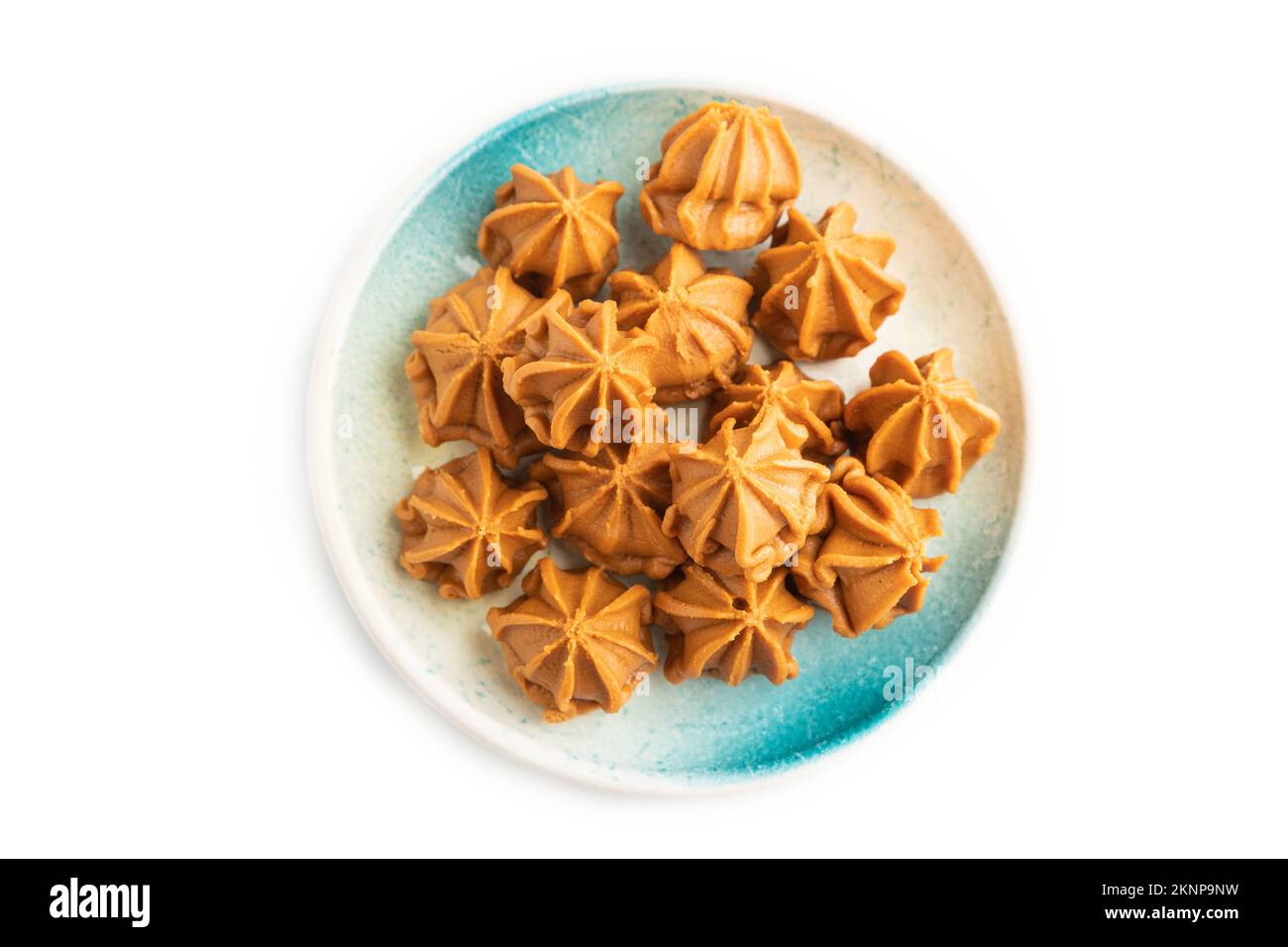 Homemade soft caramel fudge candies on blue plate isolated on white ...