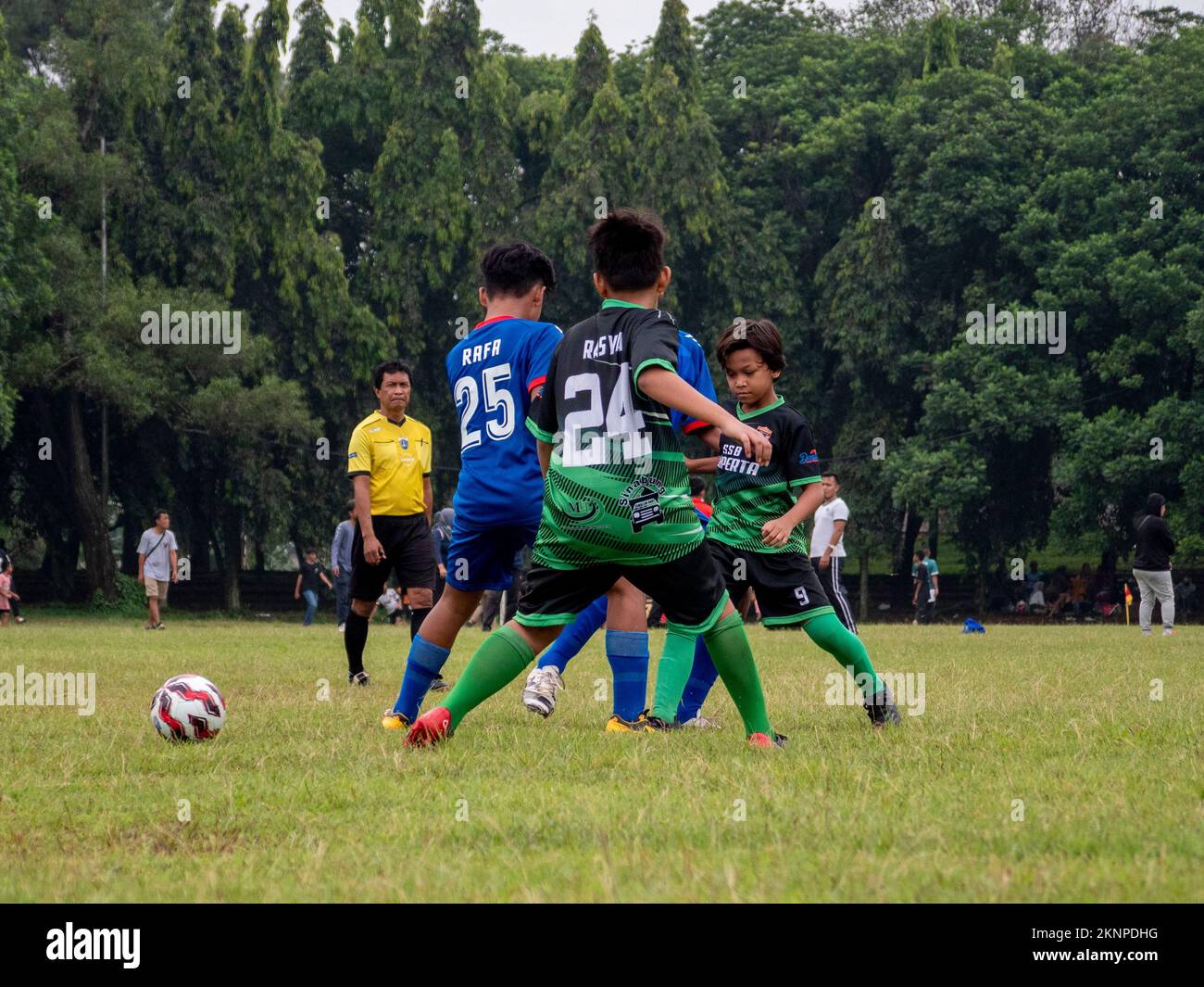 Asian Kids with blue and green uniforms playing football on the soccer ...