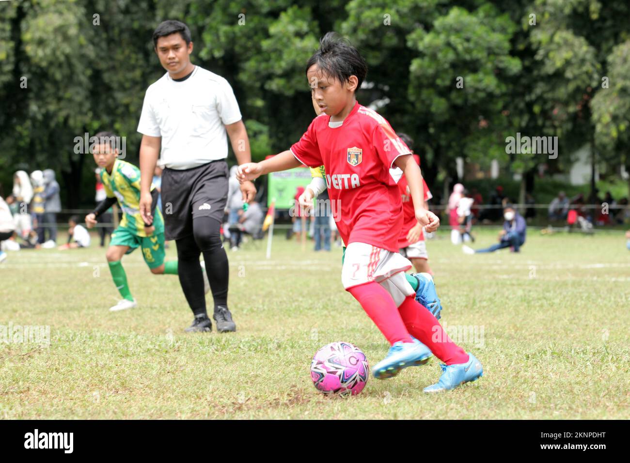 Asian Kids with red uniforms playing football on the soccer field in ...
