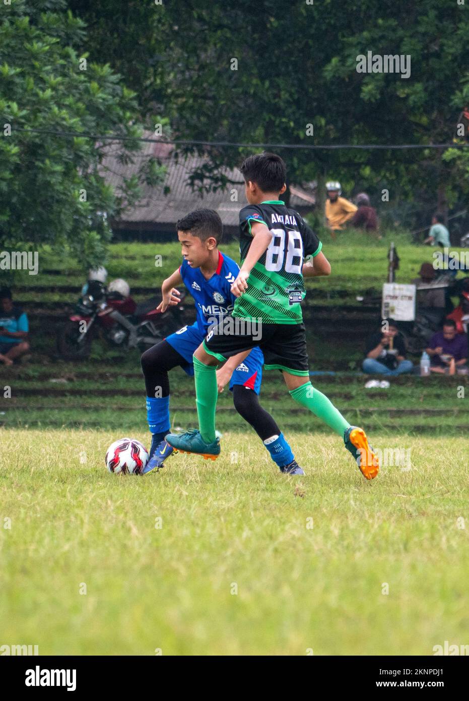 A vertical of Asian Kids with blue and green uniforms playing football ...