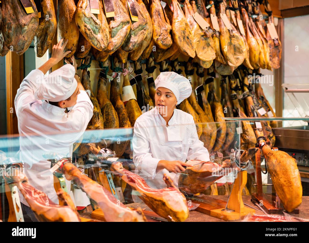 Girl and guy sellers of butcher shop working behind counter with ...