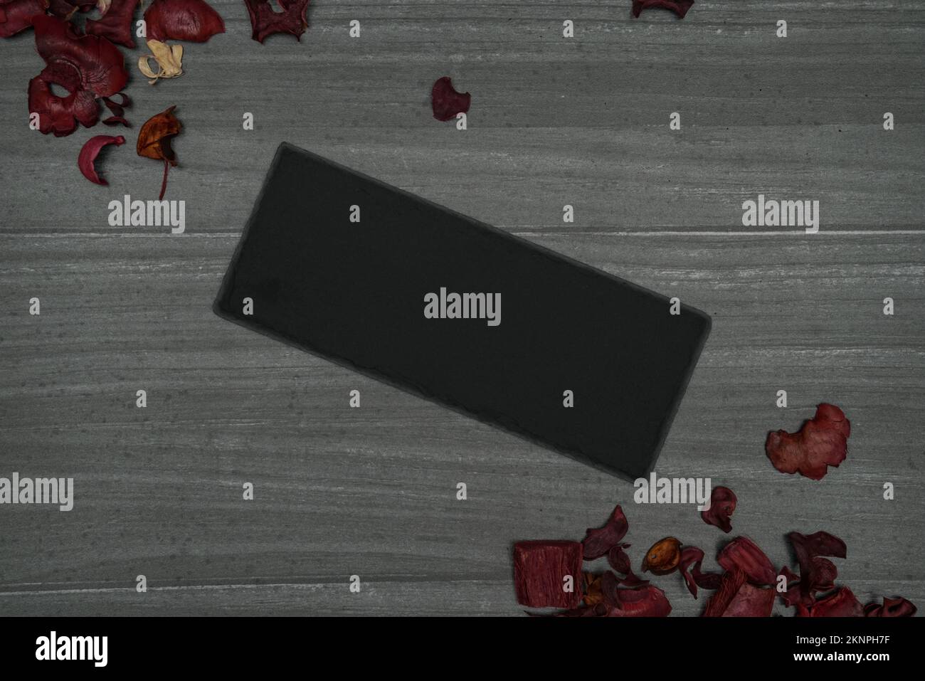 Wooden planks background, black stone rectangular plate and dry red ...