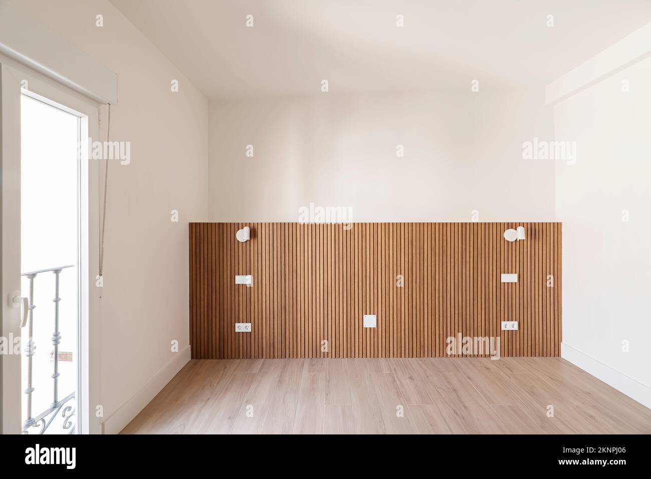 Empty bedroom with wooden headboard with attached wall sconces and ...
