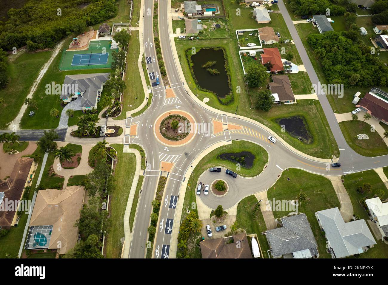 Aerial view of american suburban area with rural road roundabout intersection with moving cars ...