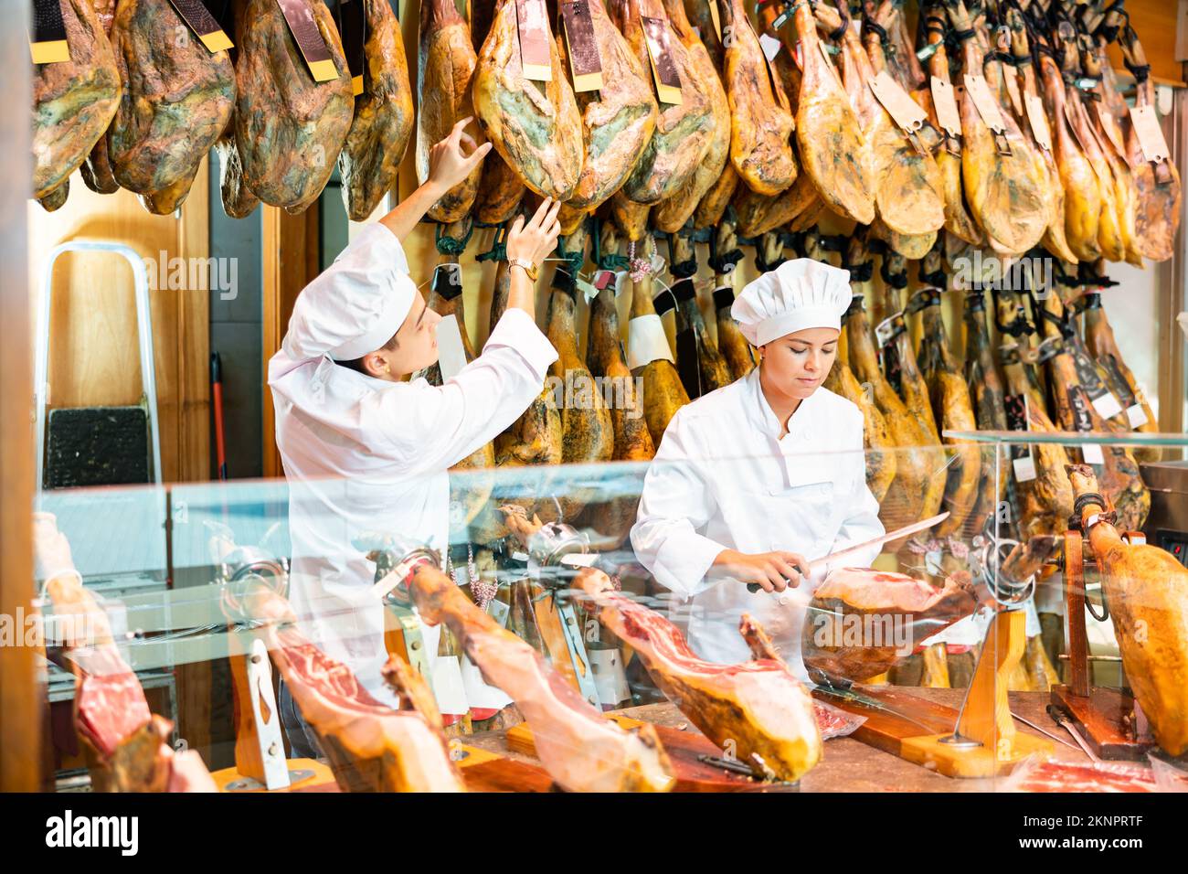 Young couple work together in butcher shop - they cut traditional ...
