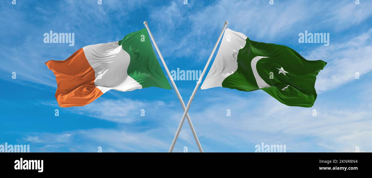 two crossed flags Pakistan and Ireland waving in wind at cloudy sky ...