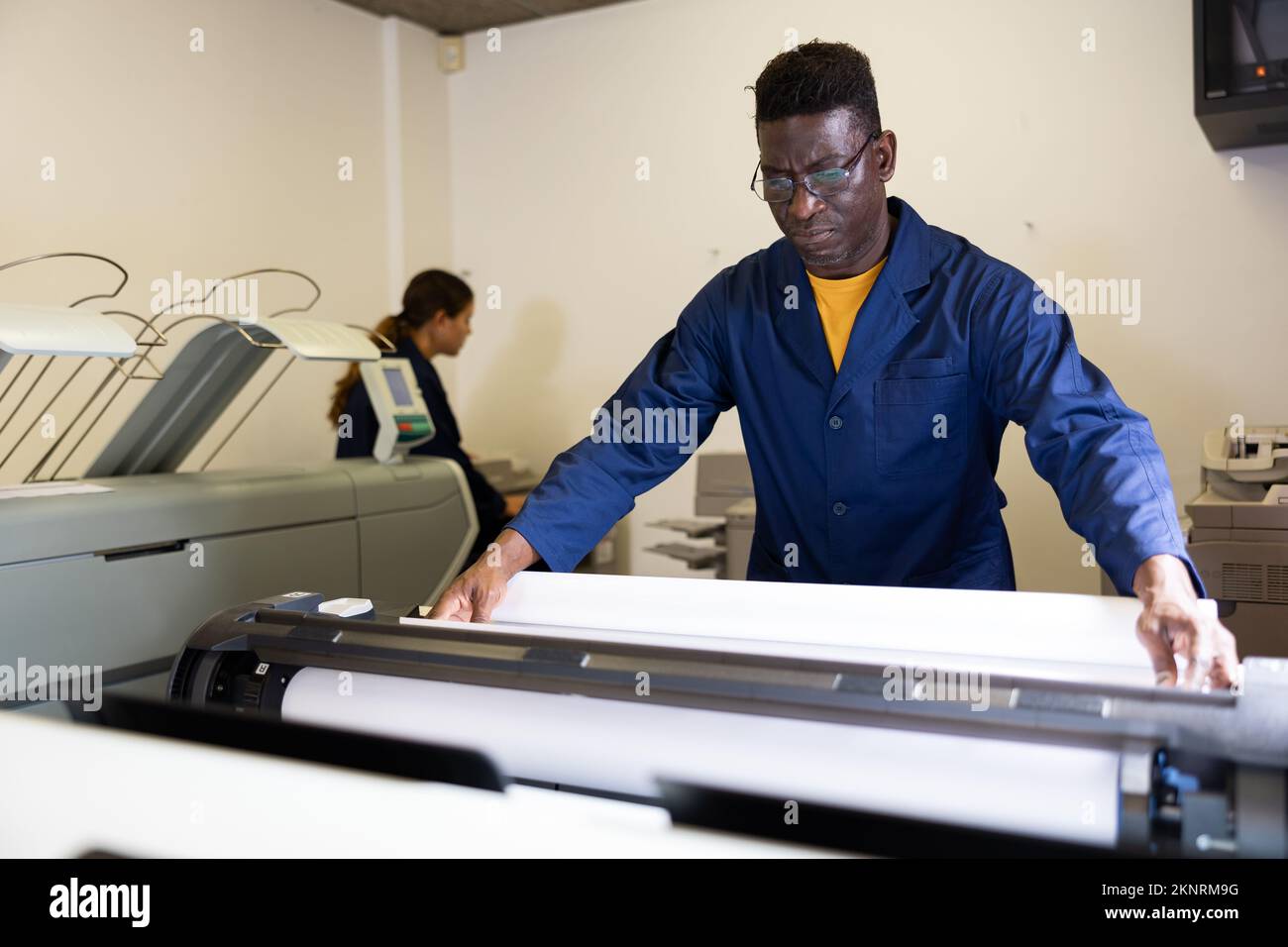 Attentive african american man uses plotter in printing shop Stock ...