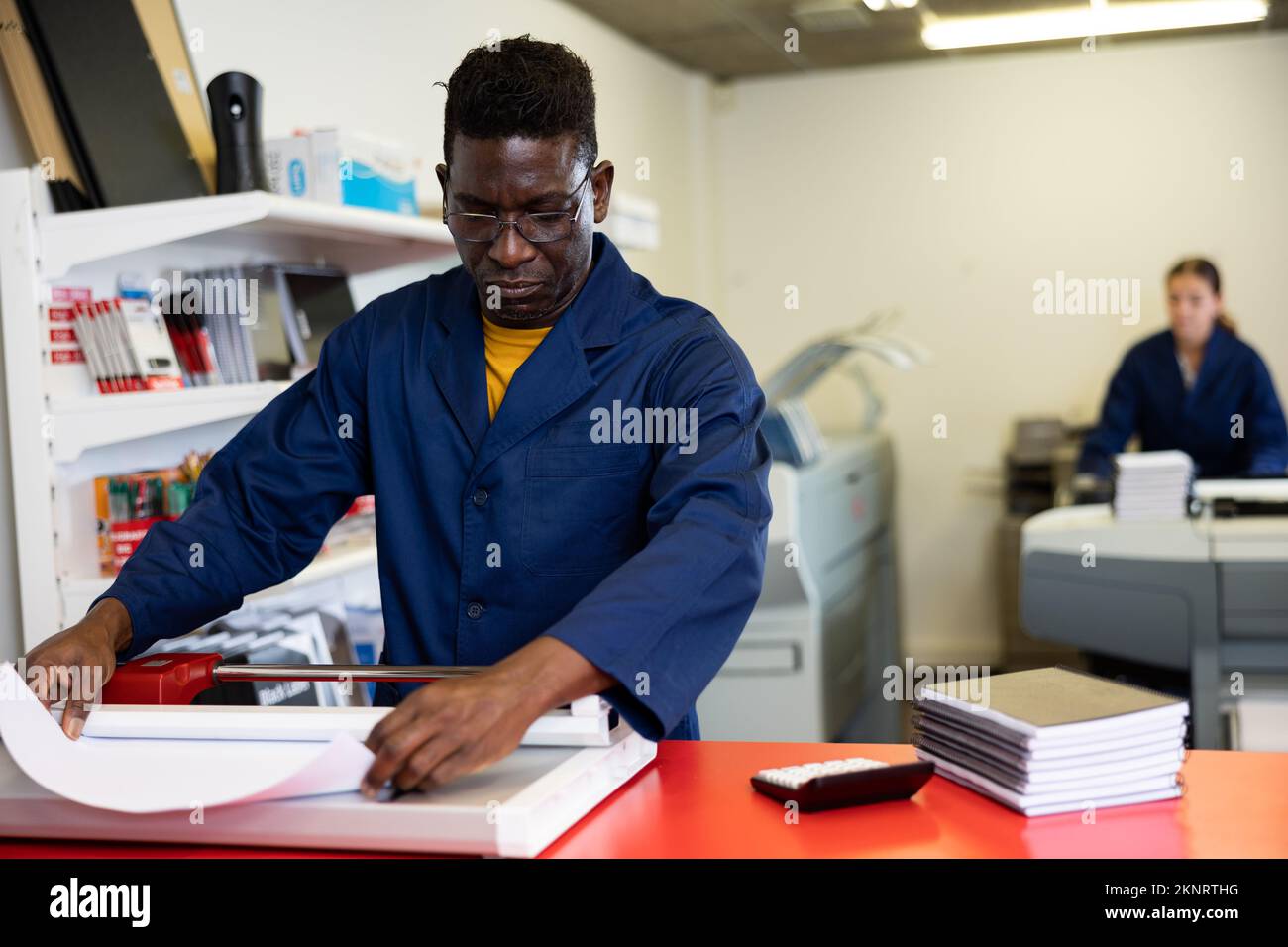 Serious print shop worker cuts paper on professional cutter Stock Photo ...