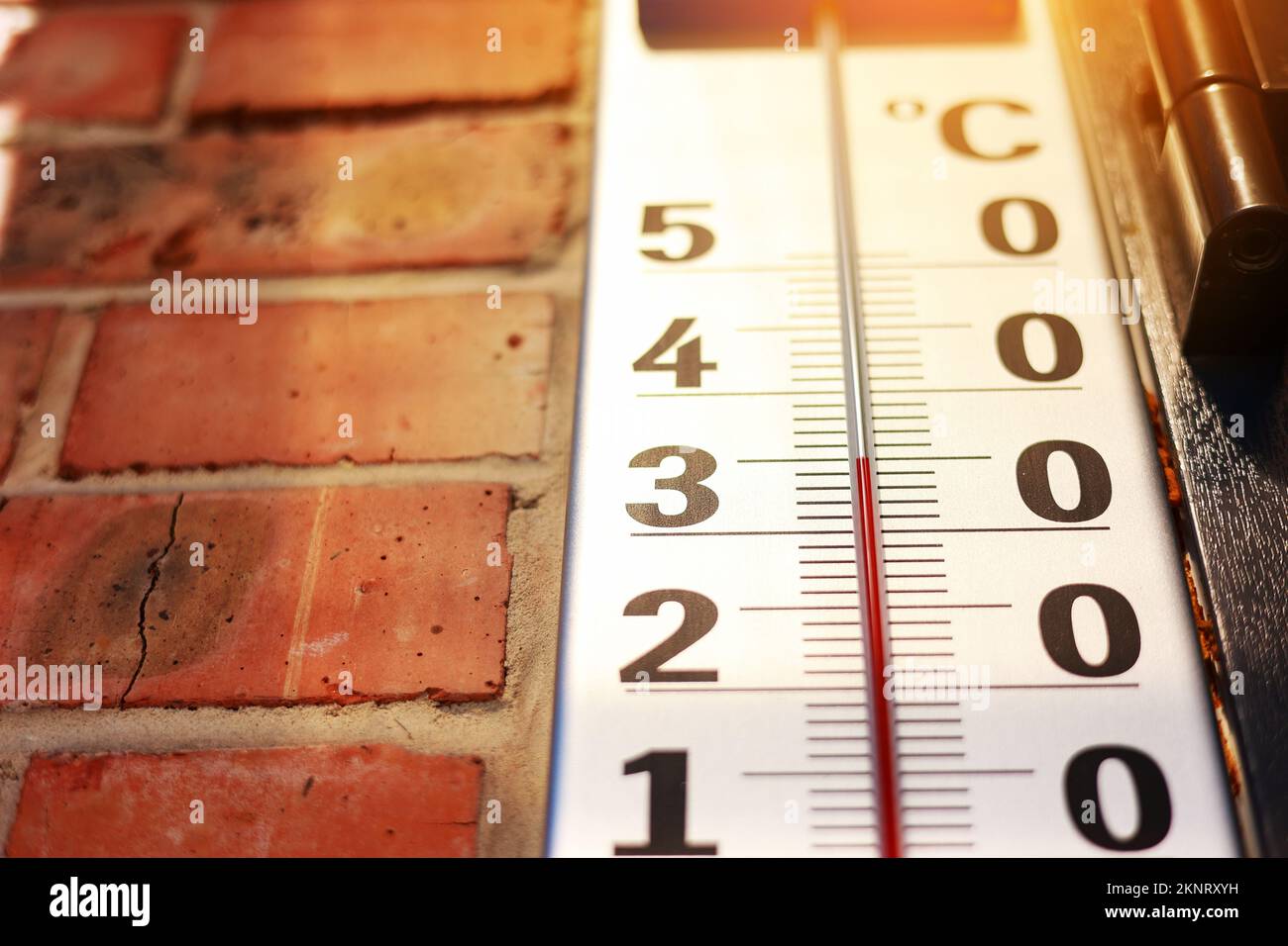 Thermometer showing high hot temperature on brick wall background ...