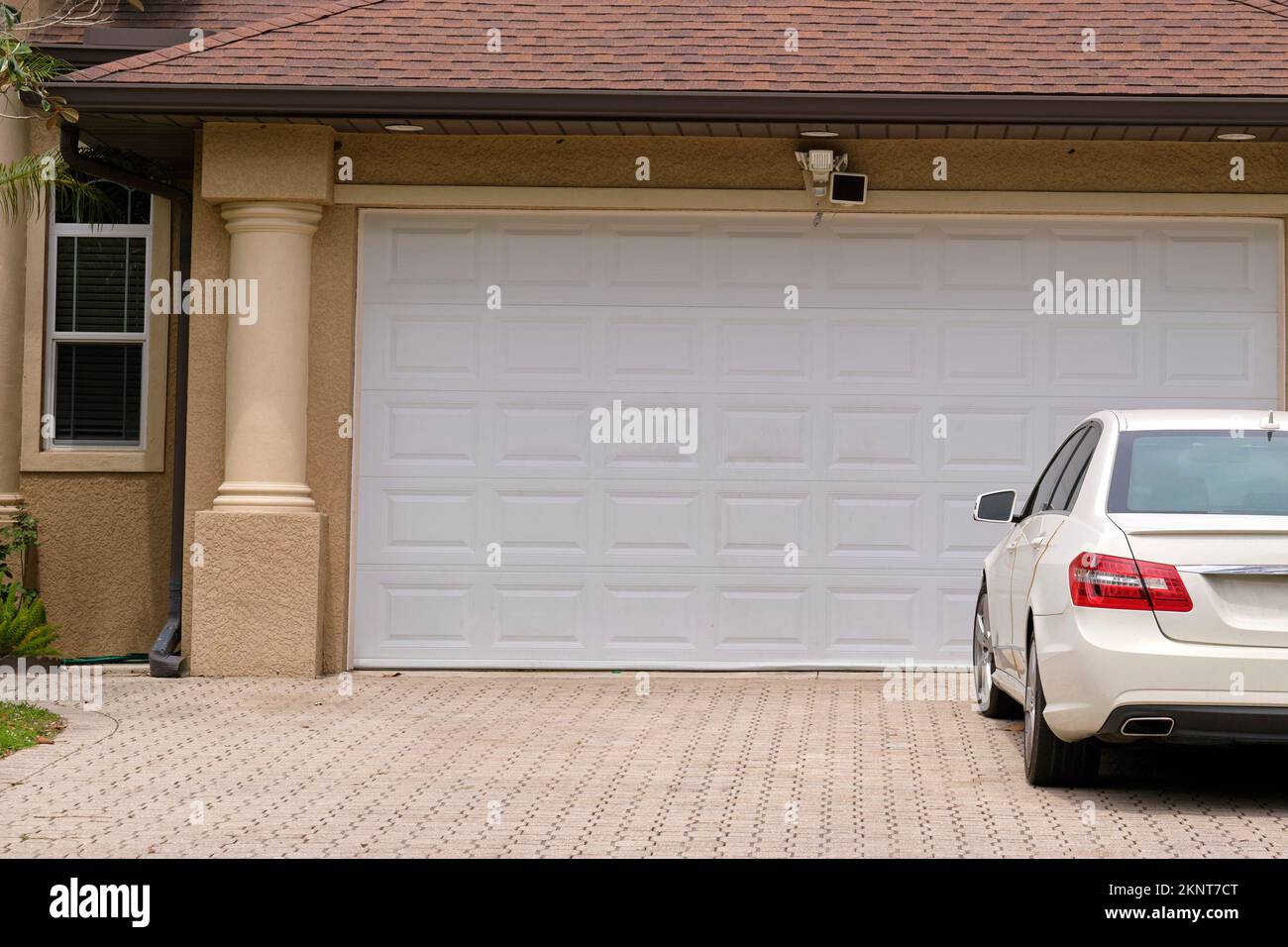 Vehicle parked in front of wide garage double door on paved driveway of ...