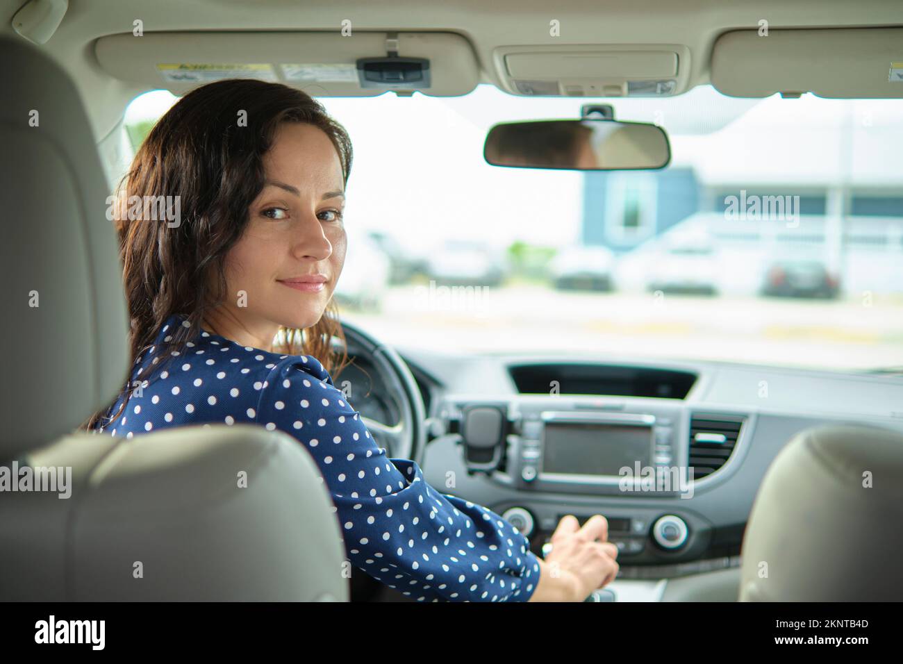 Young stylish woman driver sitting behind steering wheel of her car ...