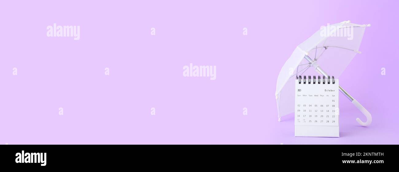 Flip paper calendar and umbrella on lilac background with space for ...