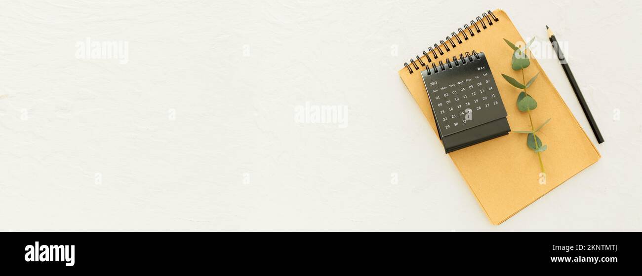 Flip paper calendar with notebook, pencil and eucalyptus branch on ...