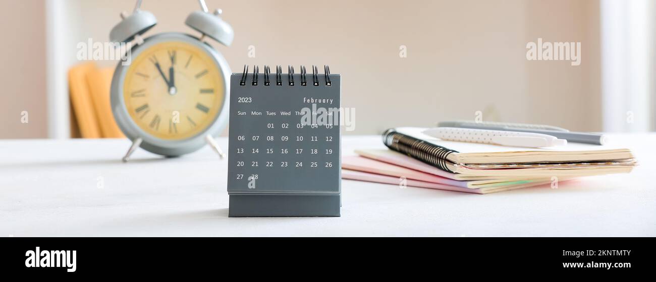 Flip paper calendar with alarm clock and notebooks on table Stock Photo ...