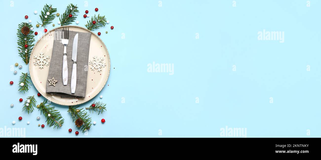 Table setting with Christmas balls and fir branches on light blue ...