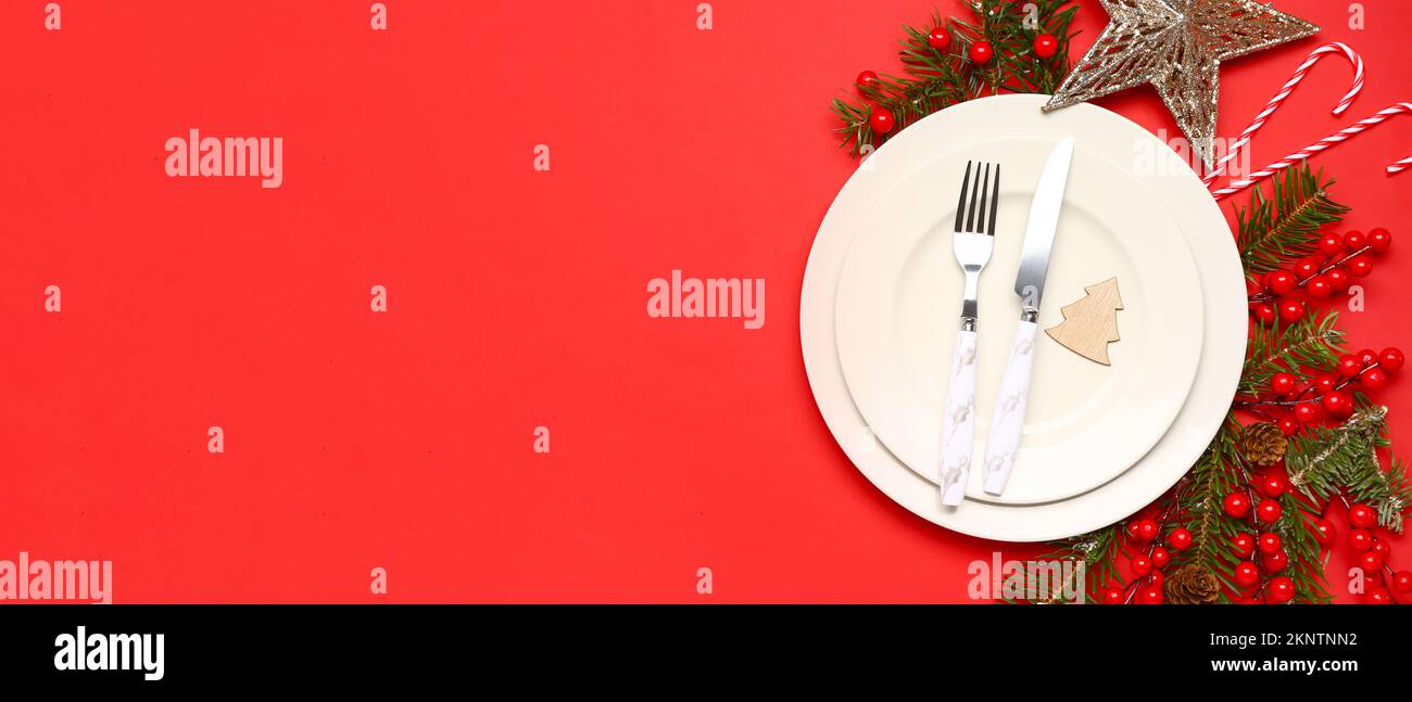 Table setting with Christmas branches and rowan berries on red background with space for text ...