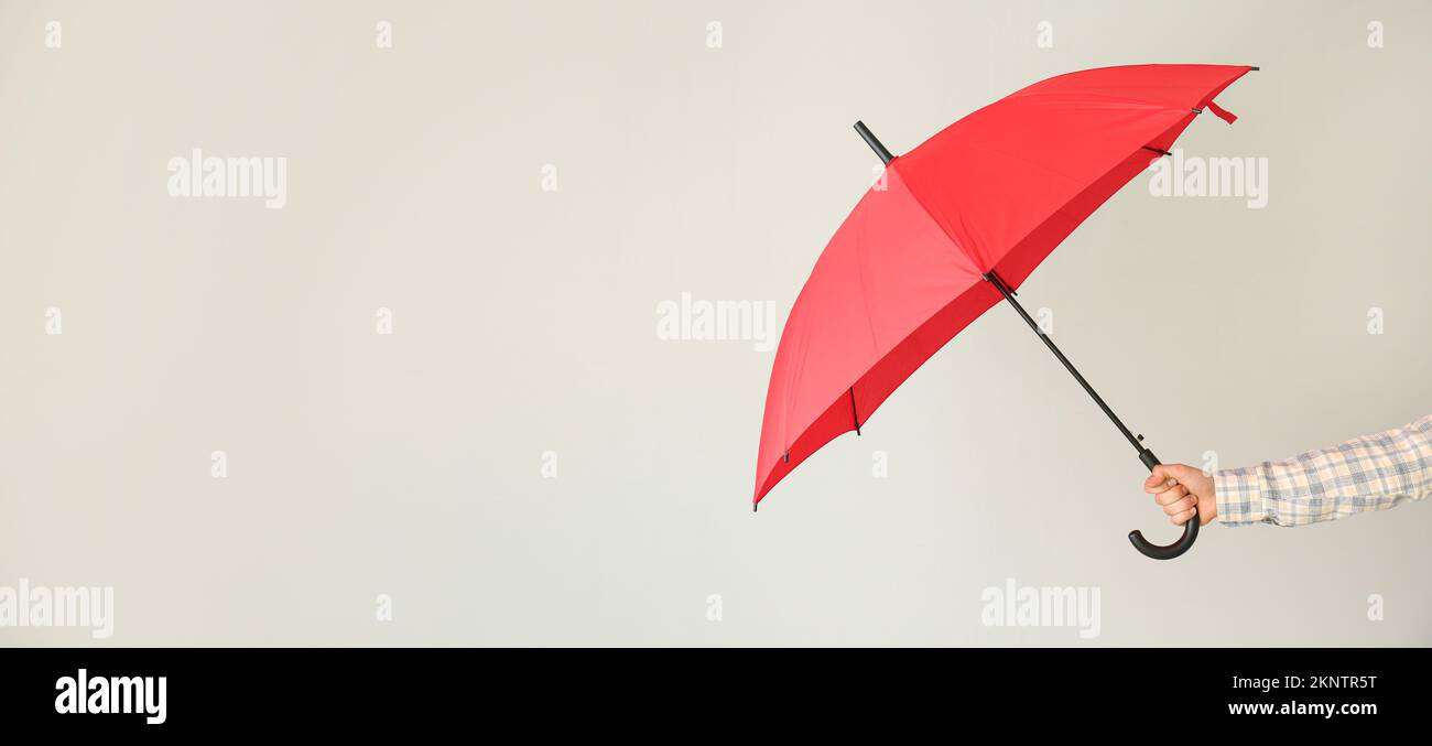Hand holding stylish red umbrella on light background with space for ...