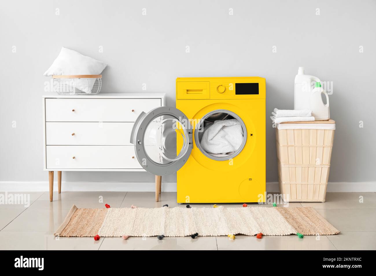 Interior of bathroom with chest of drawers, basket and modern yellow ...
