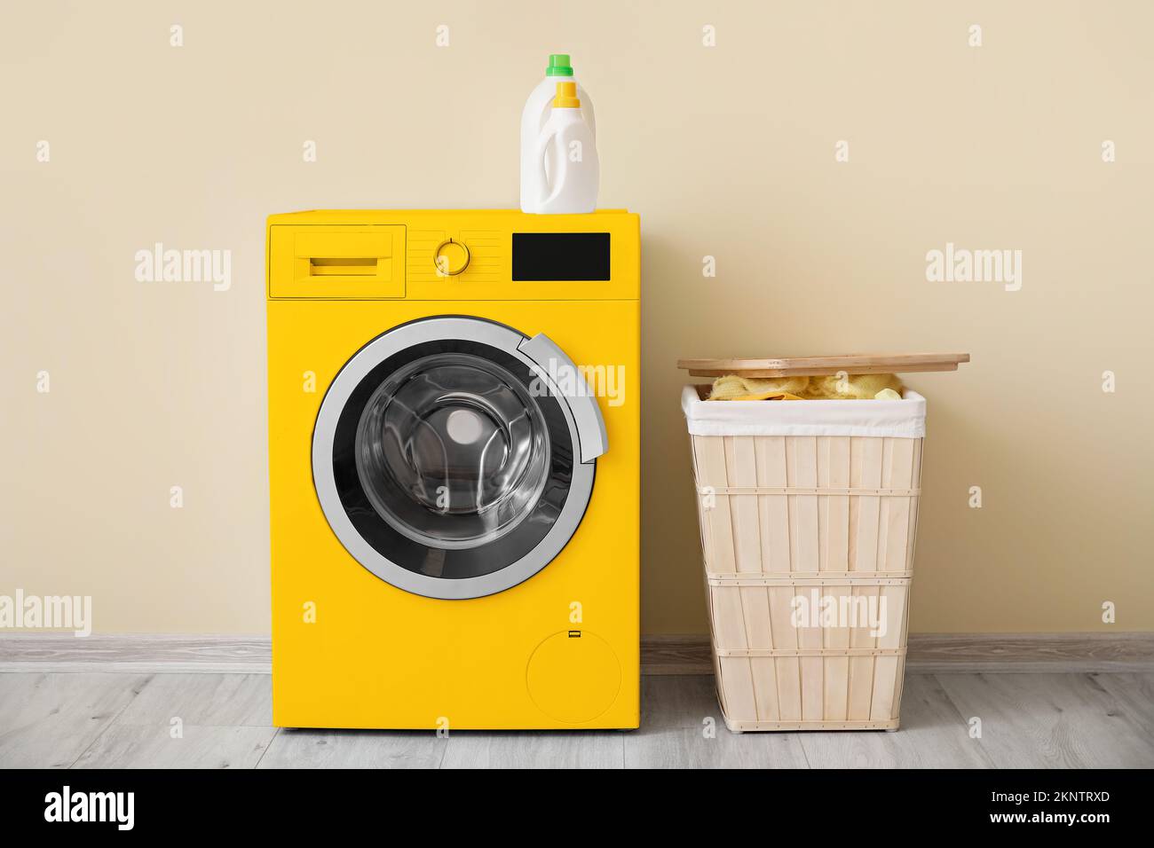 Yellow washing machine and basket with laundry near beige wall Stock ...