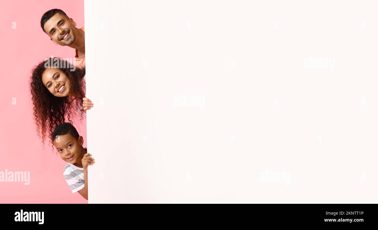 Happy interracial family with blank poster on pink background Stock ...