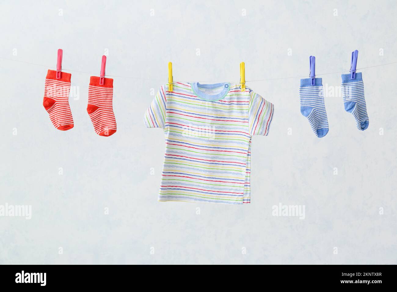 Baby clothes hanging on rope against light background Stock Photo - Alamy