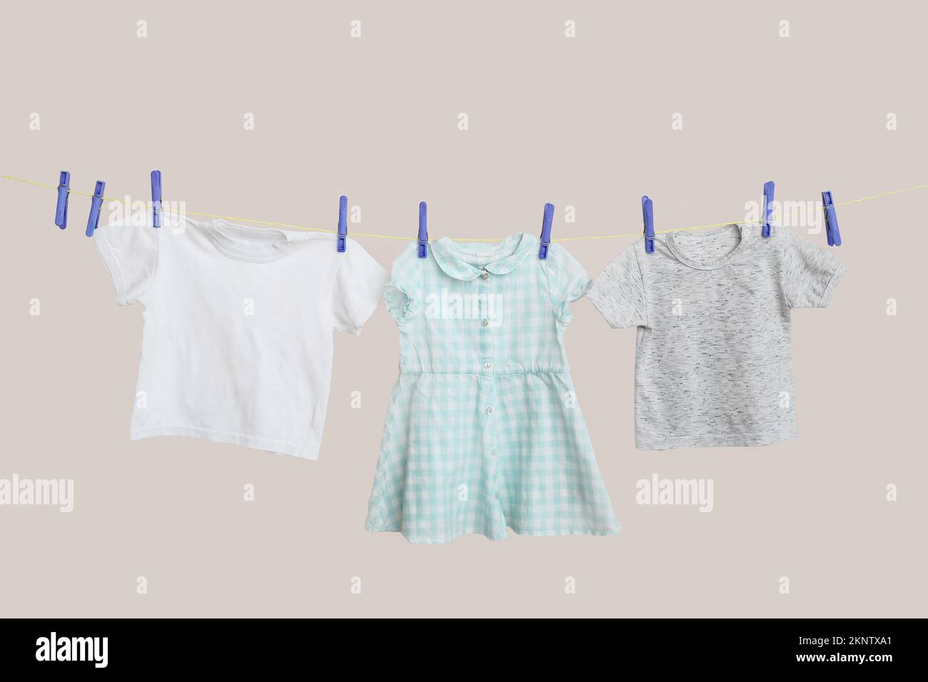Different baby clothes hanging on rope against color background Stock ...