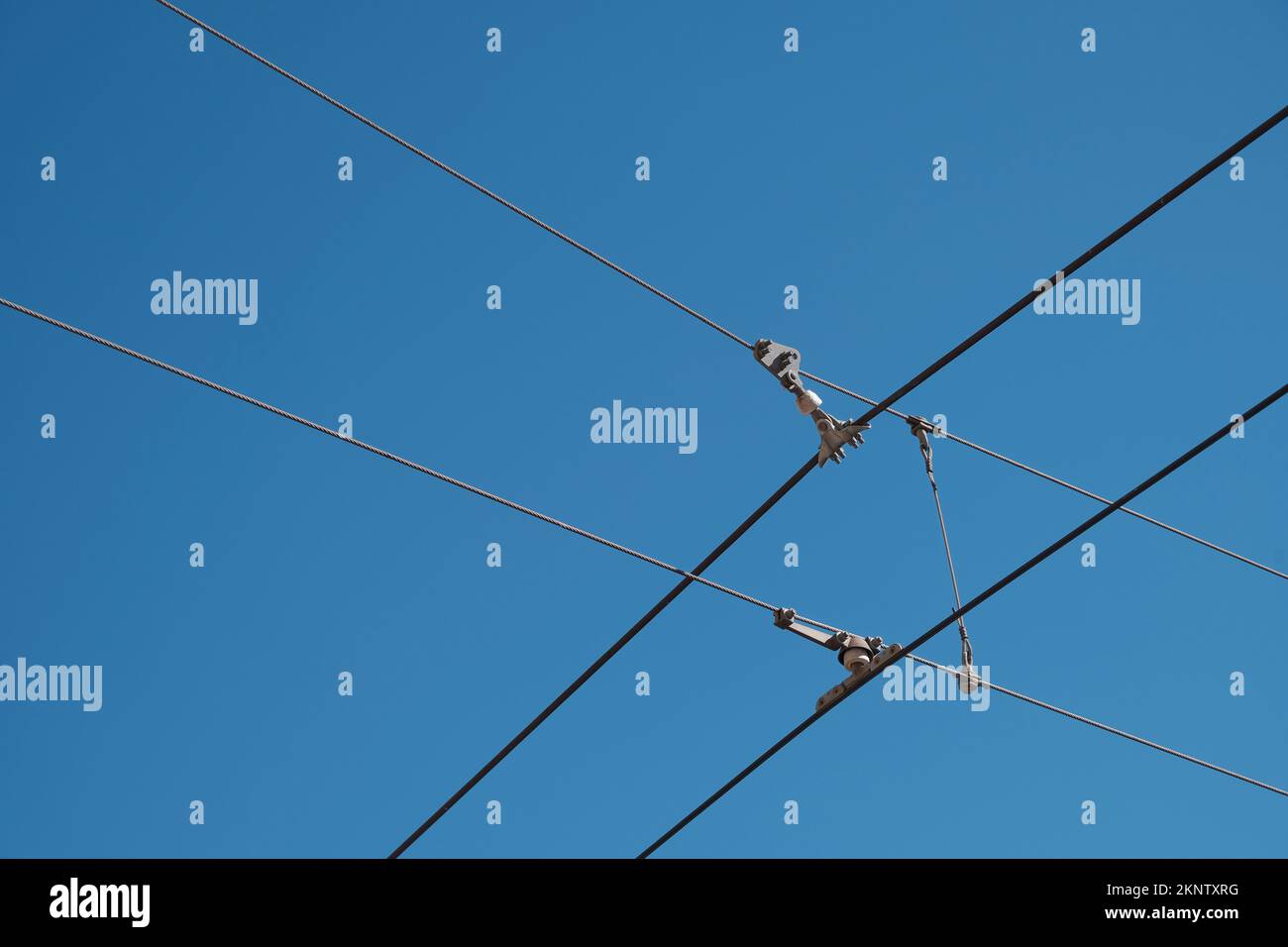 Light rail train cables cross in clear blue sky Stock Photo - Alamy