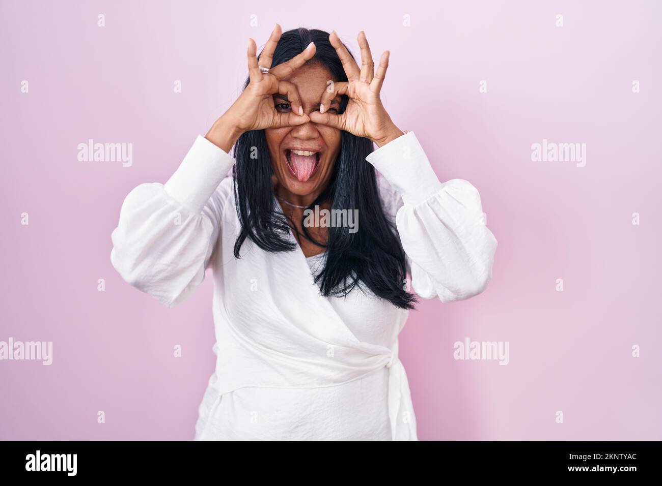 Mature hispanic woman standing over pink background doing ok gesture ...