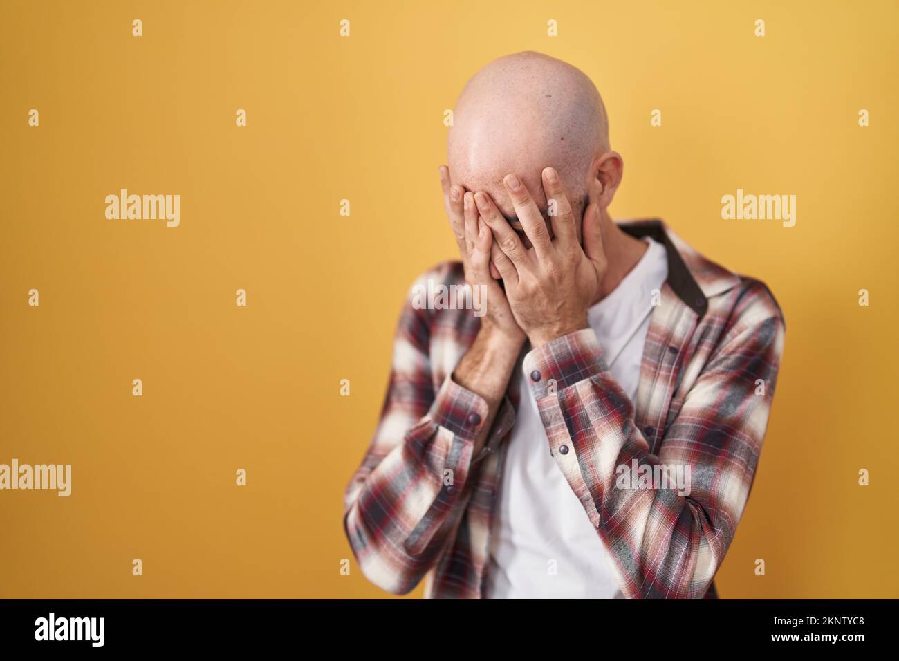 Hispanic man with beard standing over yellow background with sad ...