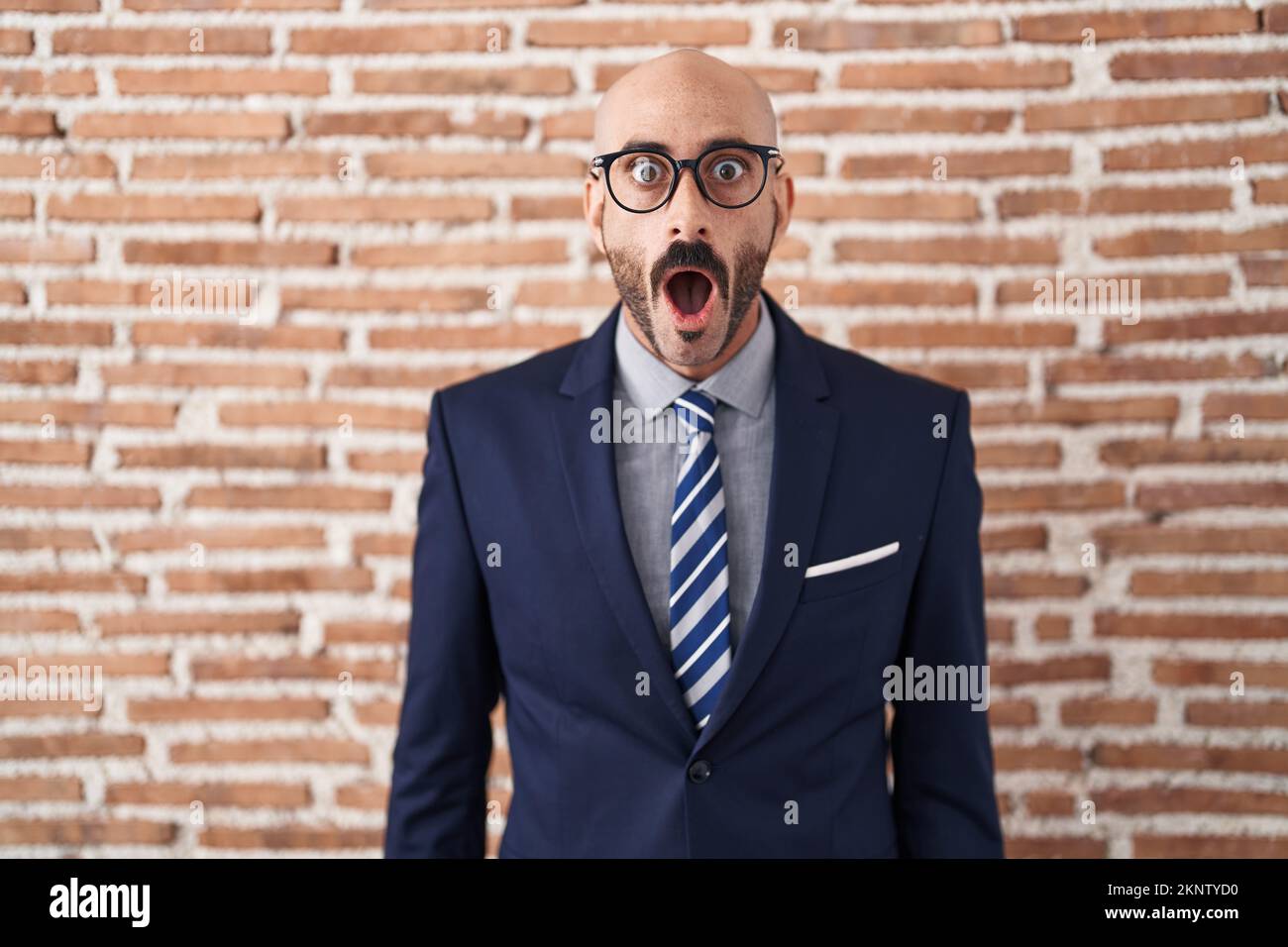 Bald man with beard wearing business clothes and glasses afraid and ...