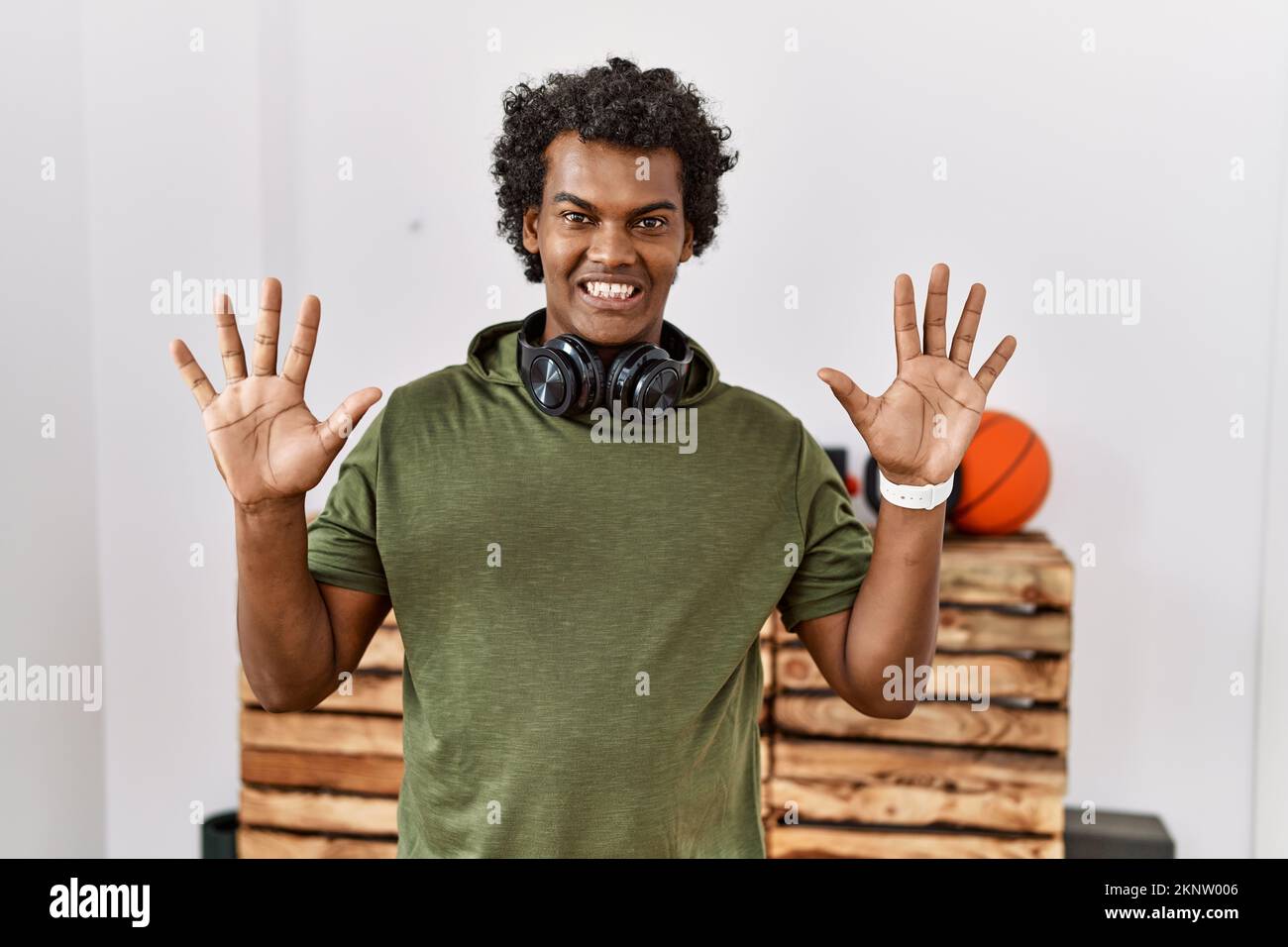 African man with curly hair wearing sportswear at the gym showing and ...