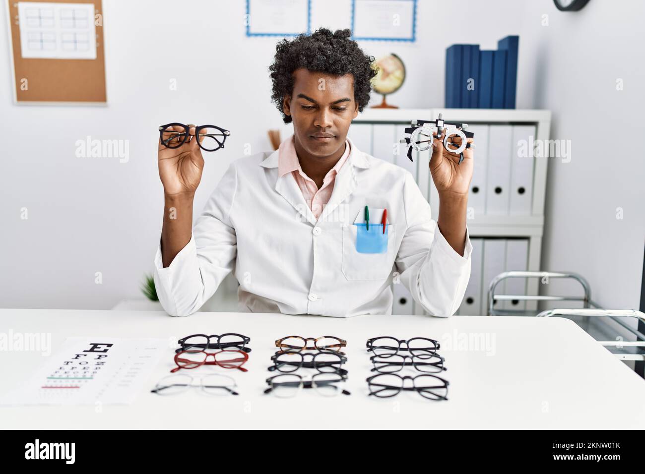 African optician man with curly hair holding optometry glasses and ...