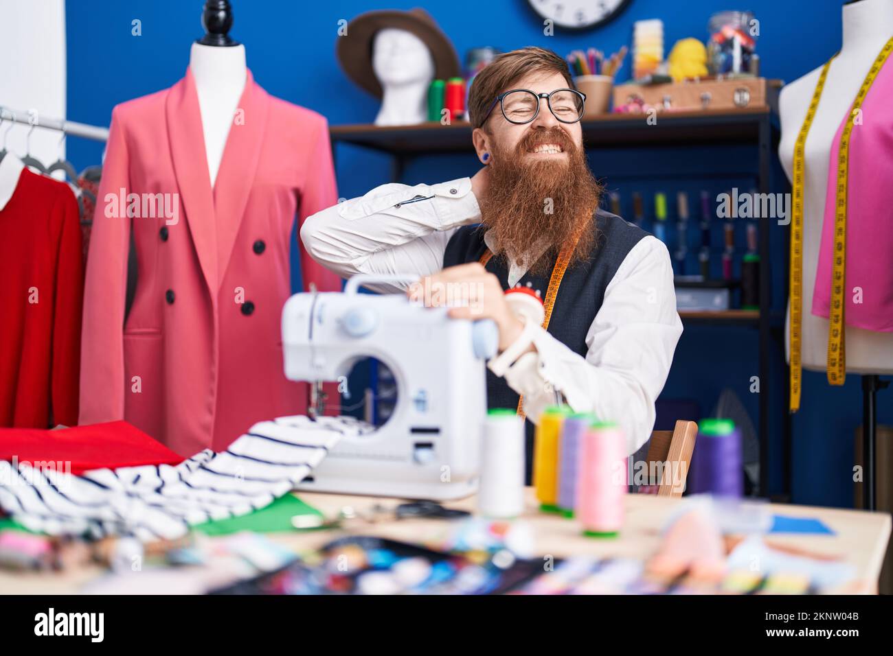 Young redhead man tailor stressed using sewing machine at clothing ...