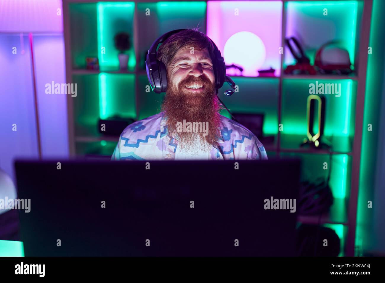 Young redhead man streamer playing video game using computer at gaming ...