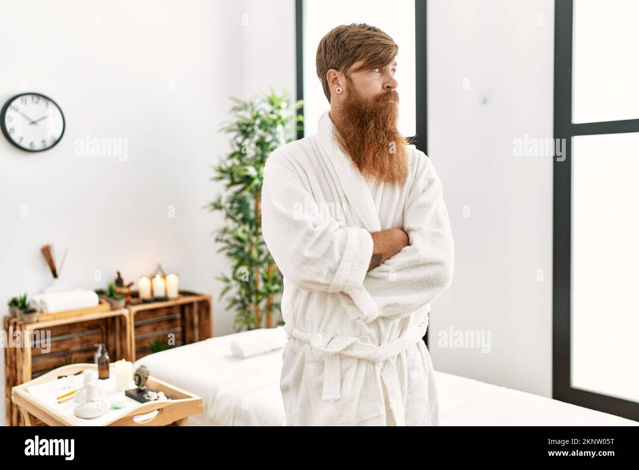Redhead man with long beard wearing bathrobe at wellness spa looking to ...