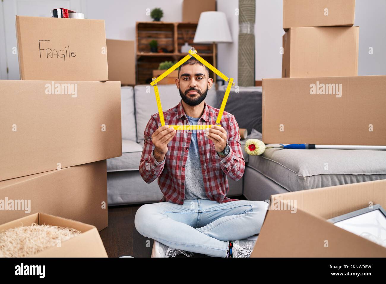 Middle east man with beard sitting on the floor at new home holding ...