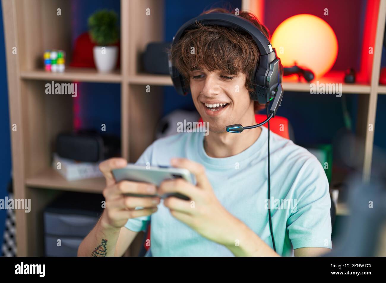 Young blond man streamer playing video game using smartphone at gaming ...