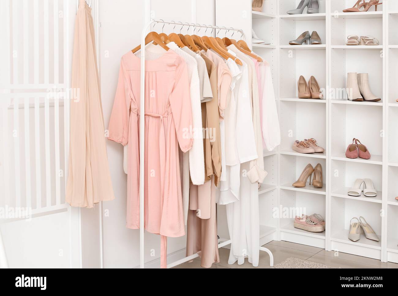 Interior of light dressing room with rack, clothes and shelving unit ...