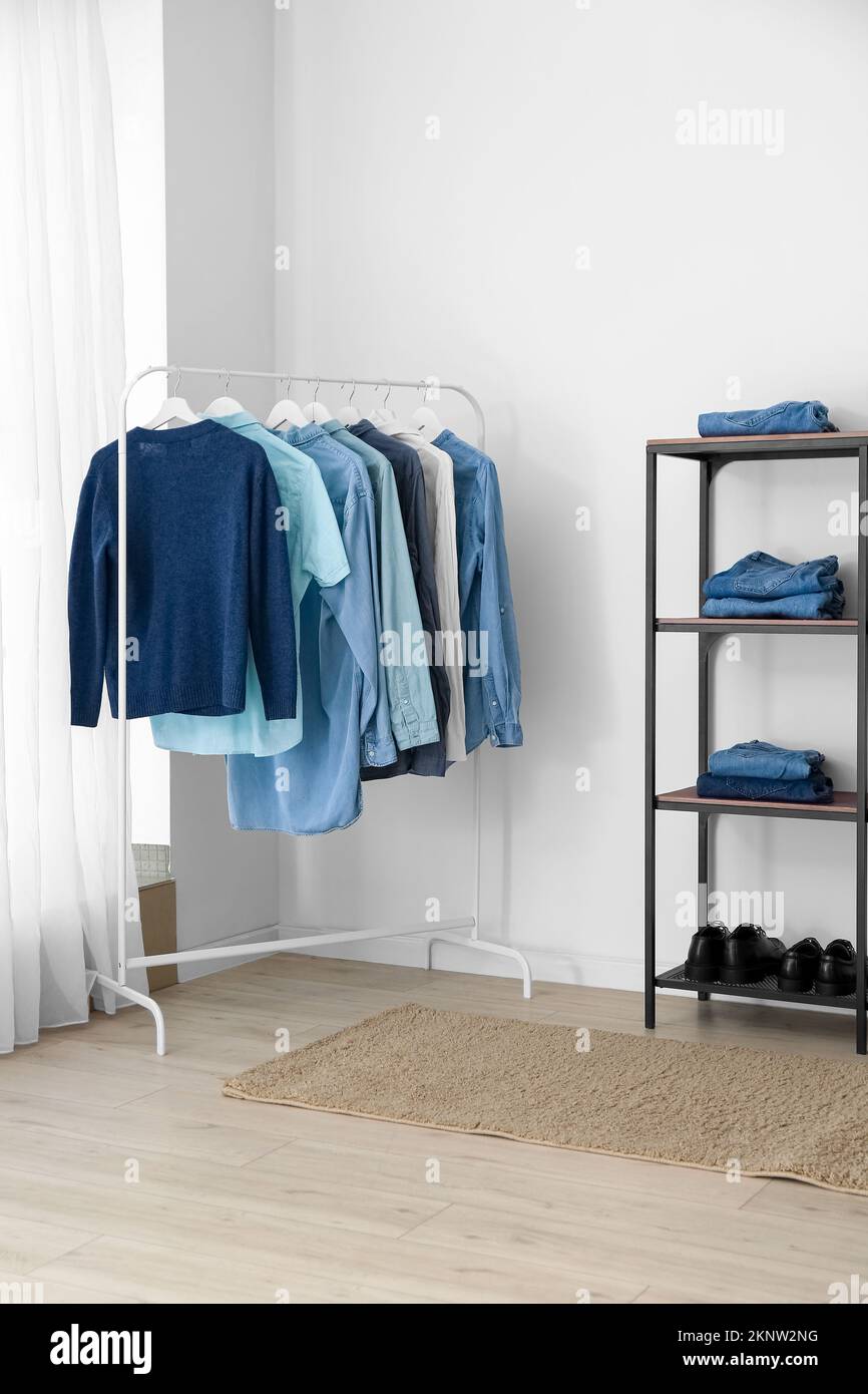 Shelving unit and rack with male clothes near light wall Stock Photo ...