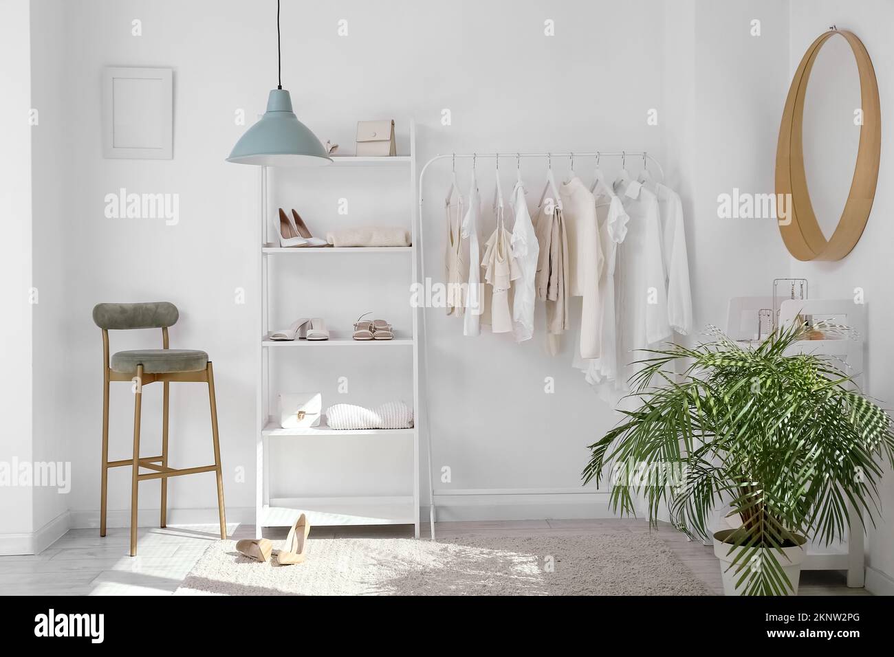Interior of light dressing room with rack, clothes and shelving unit ...